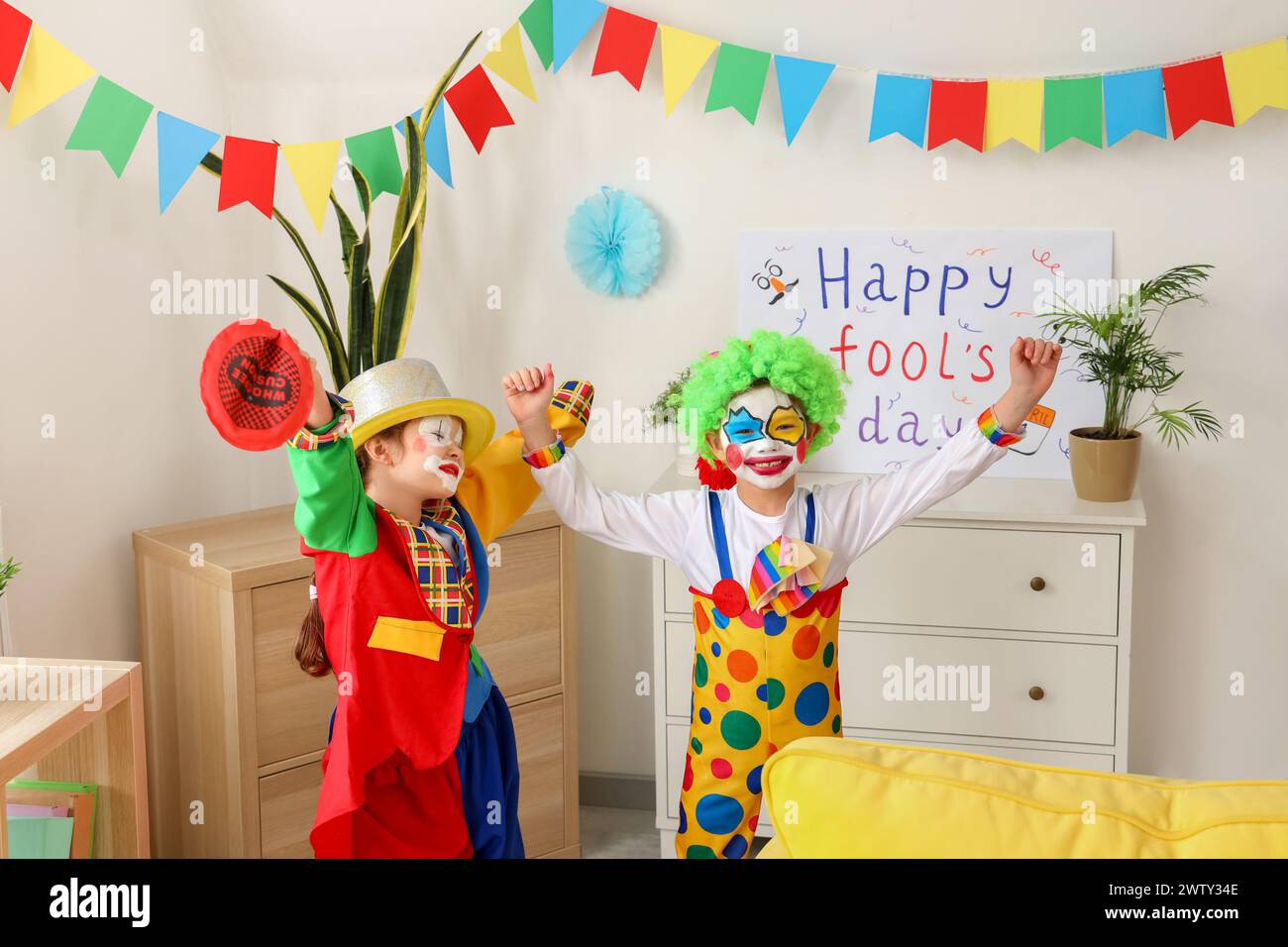 Funny little children in clown costumes with whoopee cushion at home ...