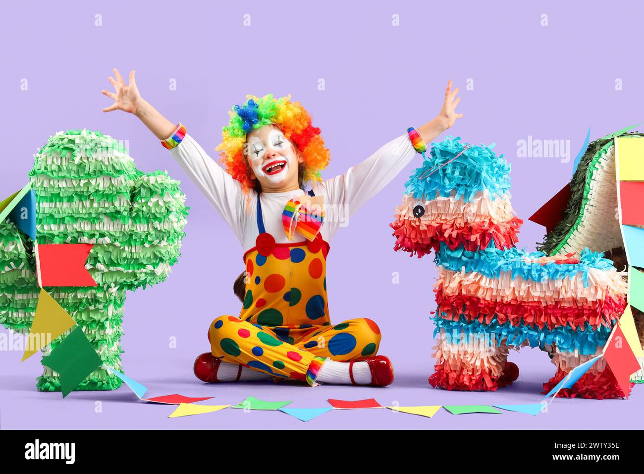 Funny little girl in clown costume with Mexican pinatas on lilac ...