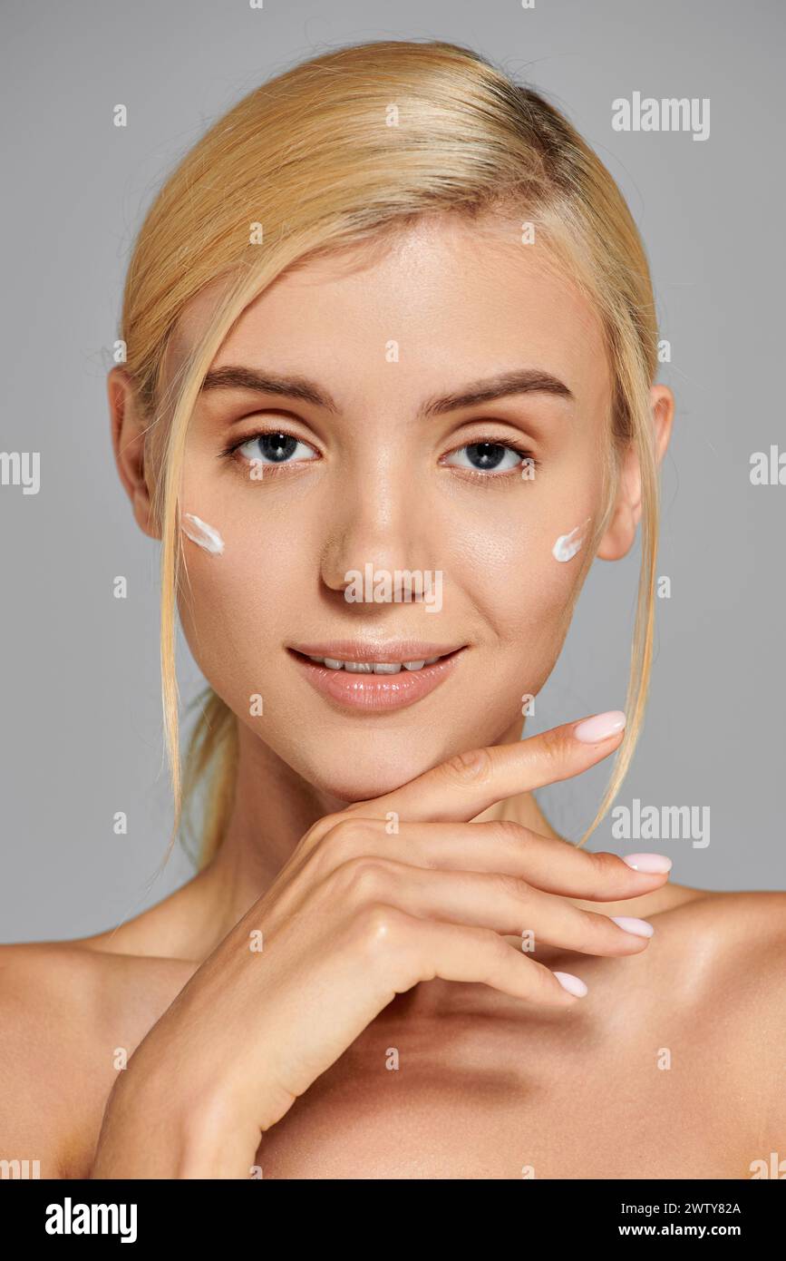 portrait alluring young woman with cream on cheeks touching her chin ...