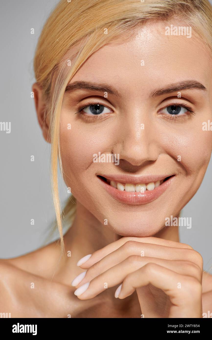 pretty young woman with grey eyes smiling broadly and touching chin ...