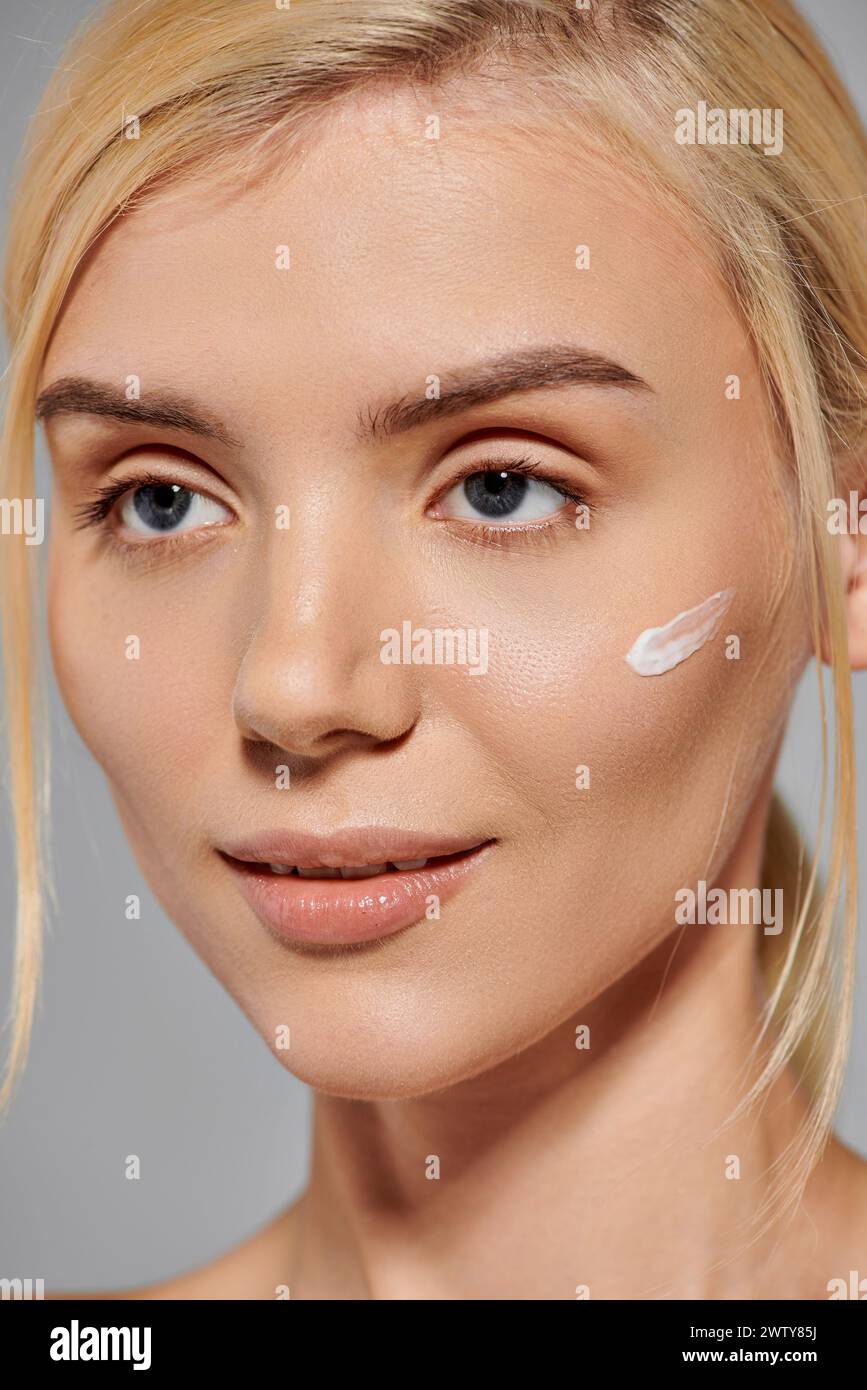 alluring young woman face with perfect glowing skin and cream on cheek ...