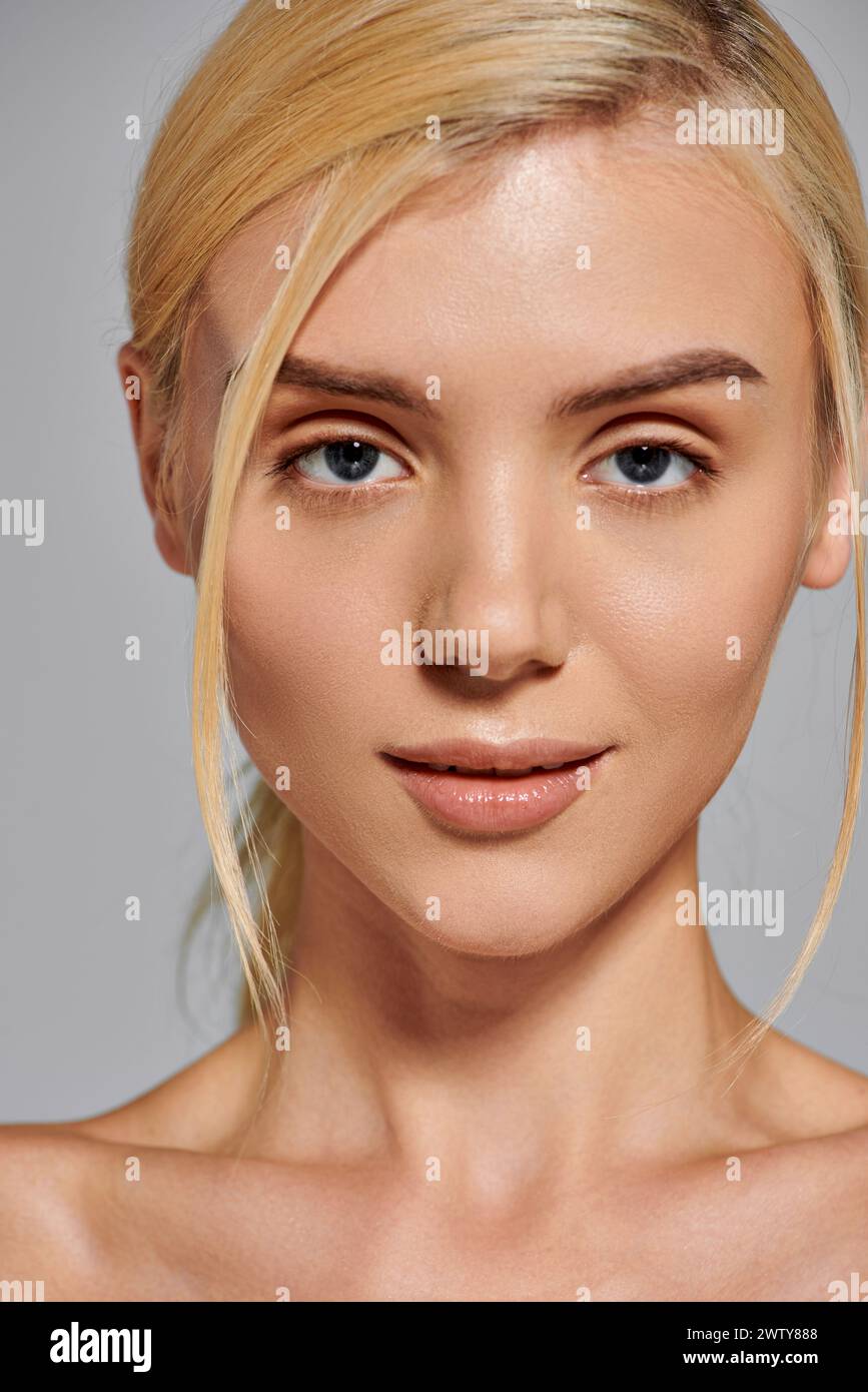 beautiful young adult woman with confident look and light smile in gray ...