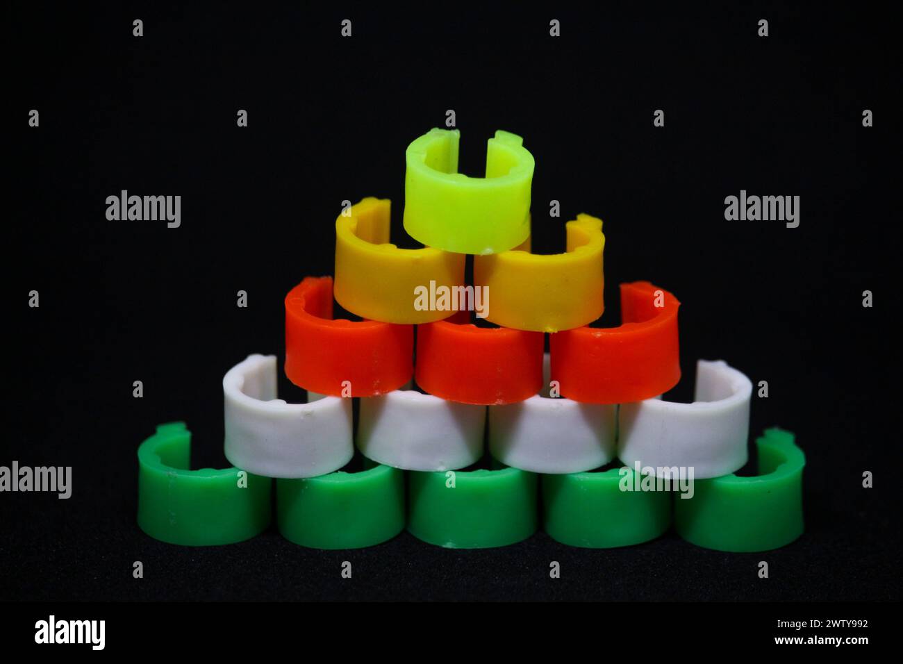 A stack of colorful plastic rings for pigeons on a dark background ...