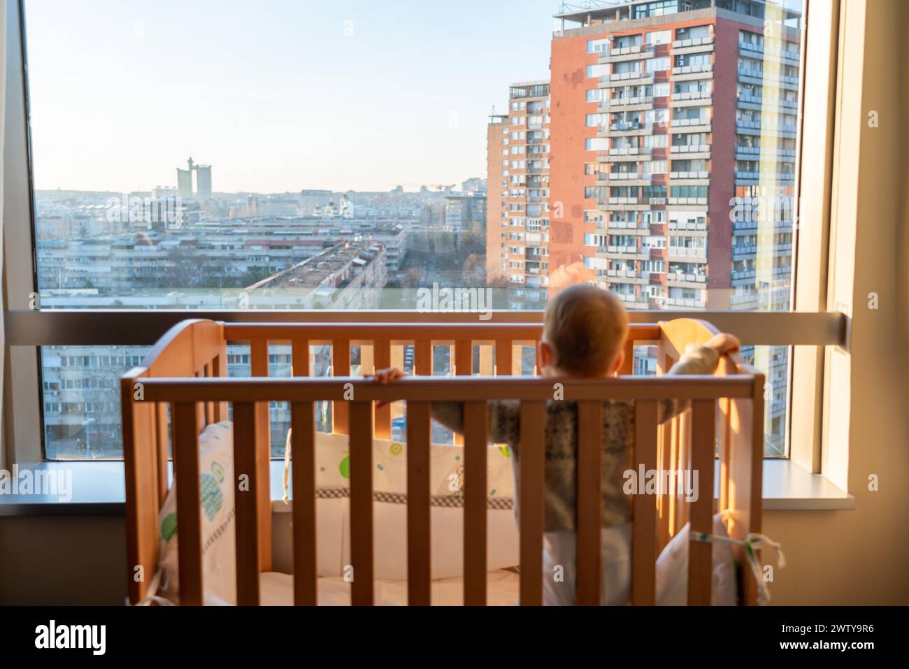 Baby looking out the panoramic window while standing in a crib Stock ...
