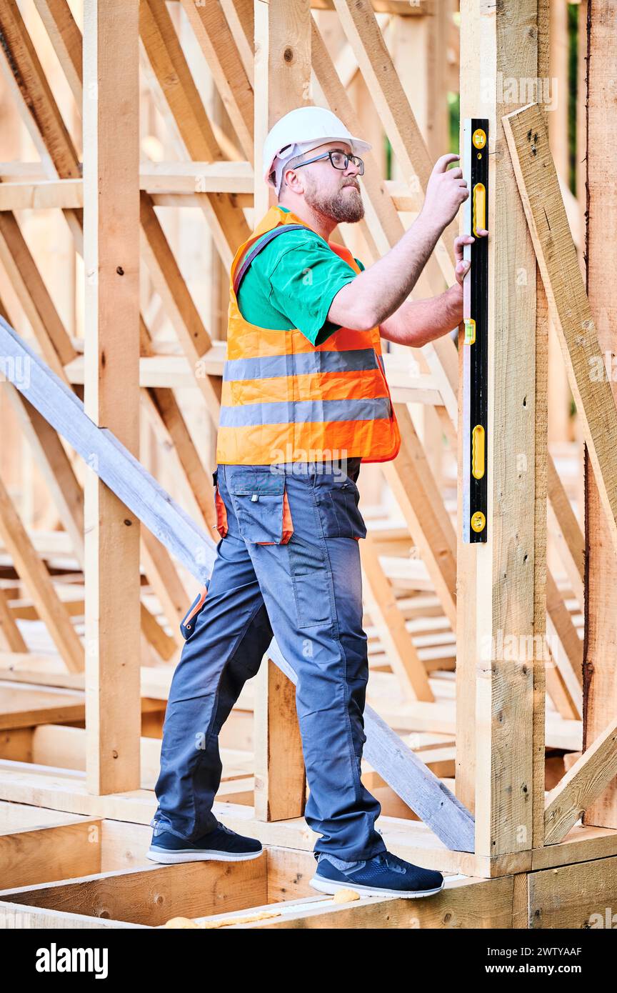 Carpenter constructing two-storey wooden frame house. Man inspects ...