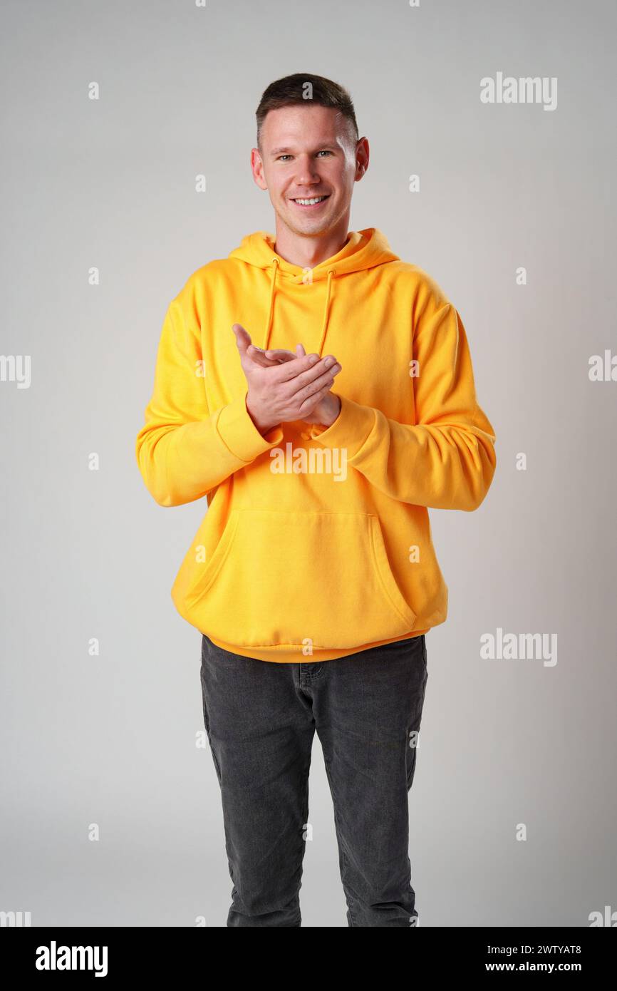 Young man clapping hands against gray background Stock Photo - Alamy