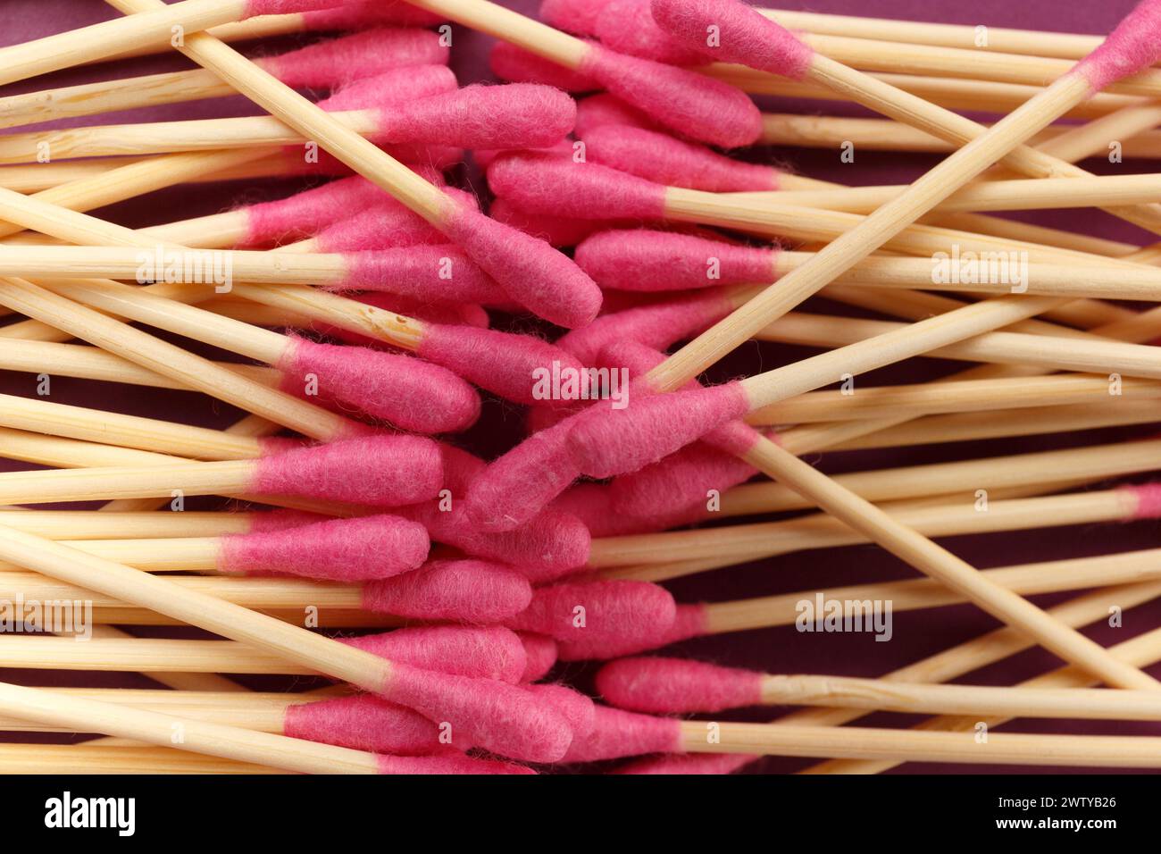 Pink bamboo cotton swabs buds sticks are scattered on a purple ...