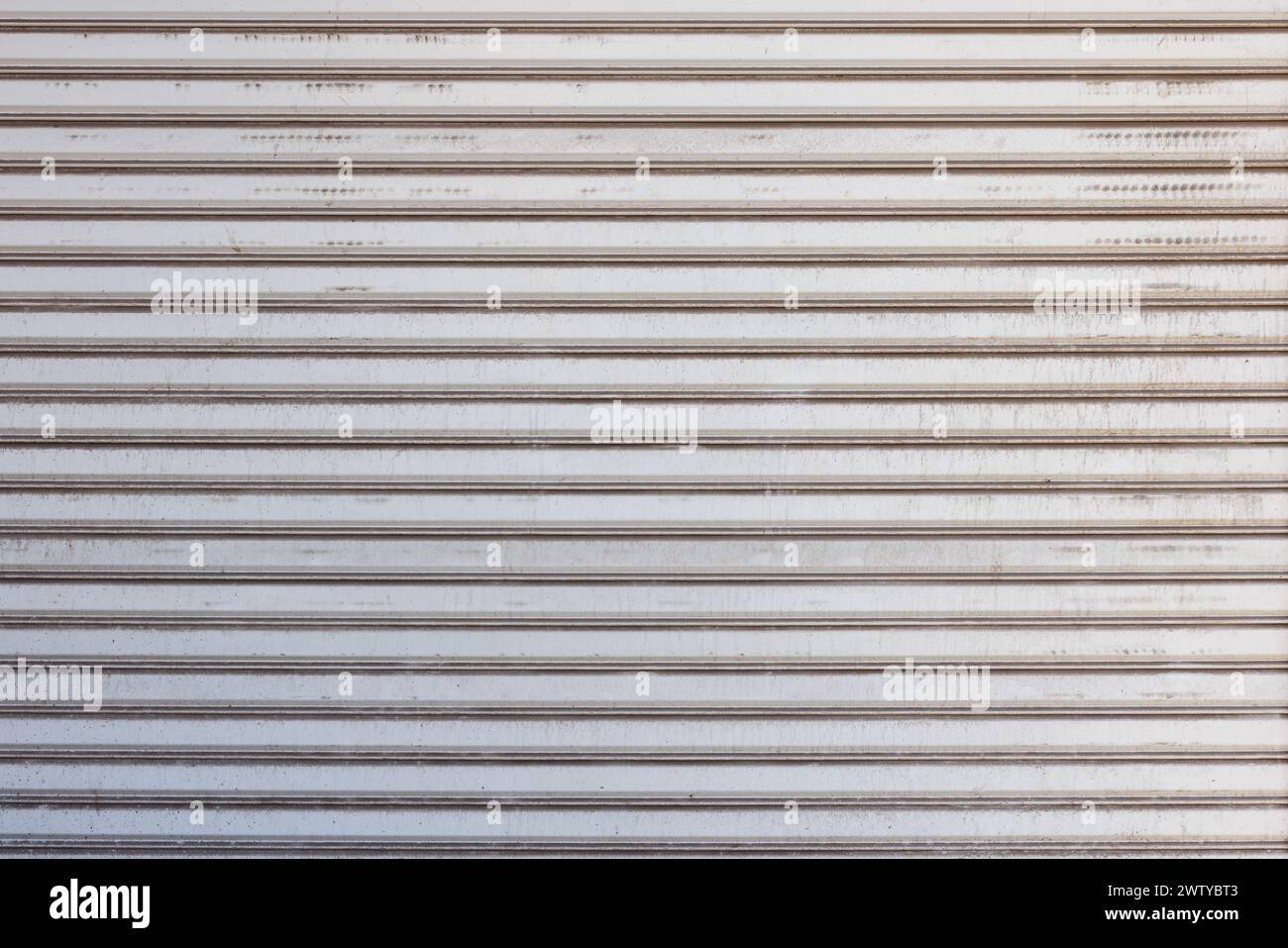 Closeup of a weathered metal shutter with horizontal folding lines ...