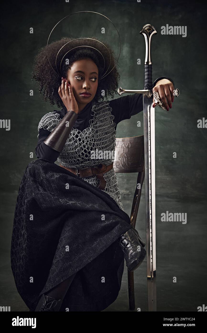 Beautiful young African woman, medieval warrior sitting on chair ...