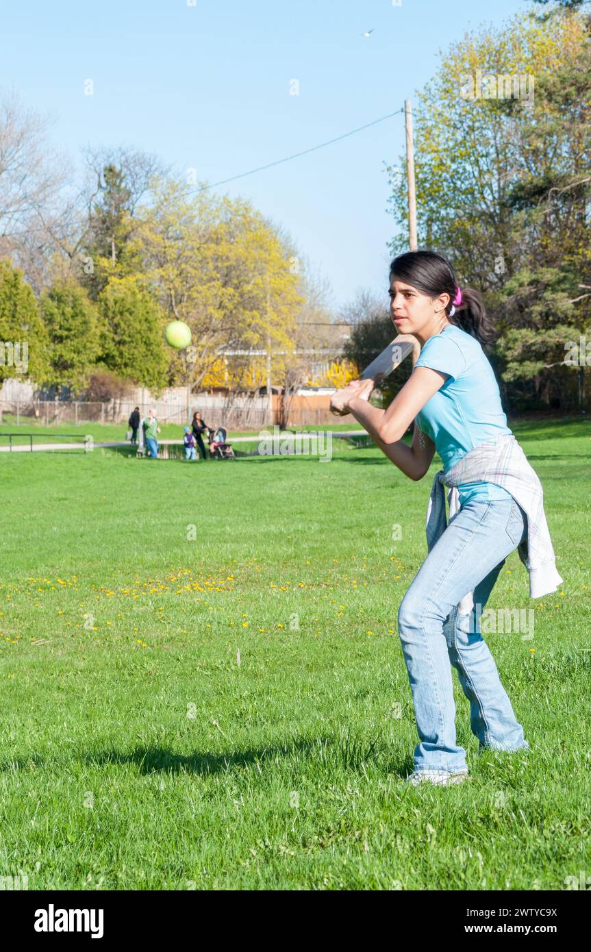 Female teenager girl batting in a public park, playing baseball Stock ...