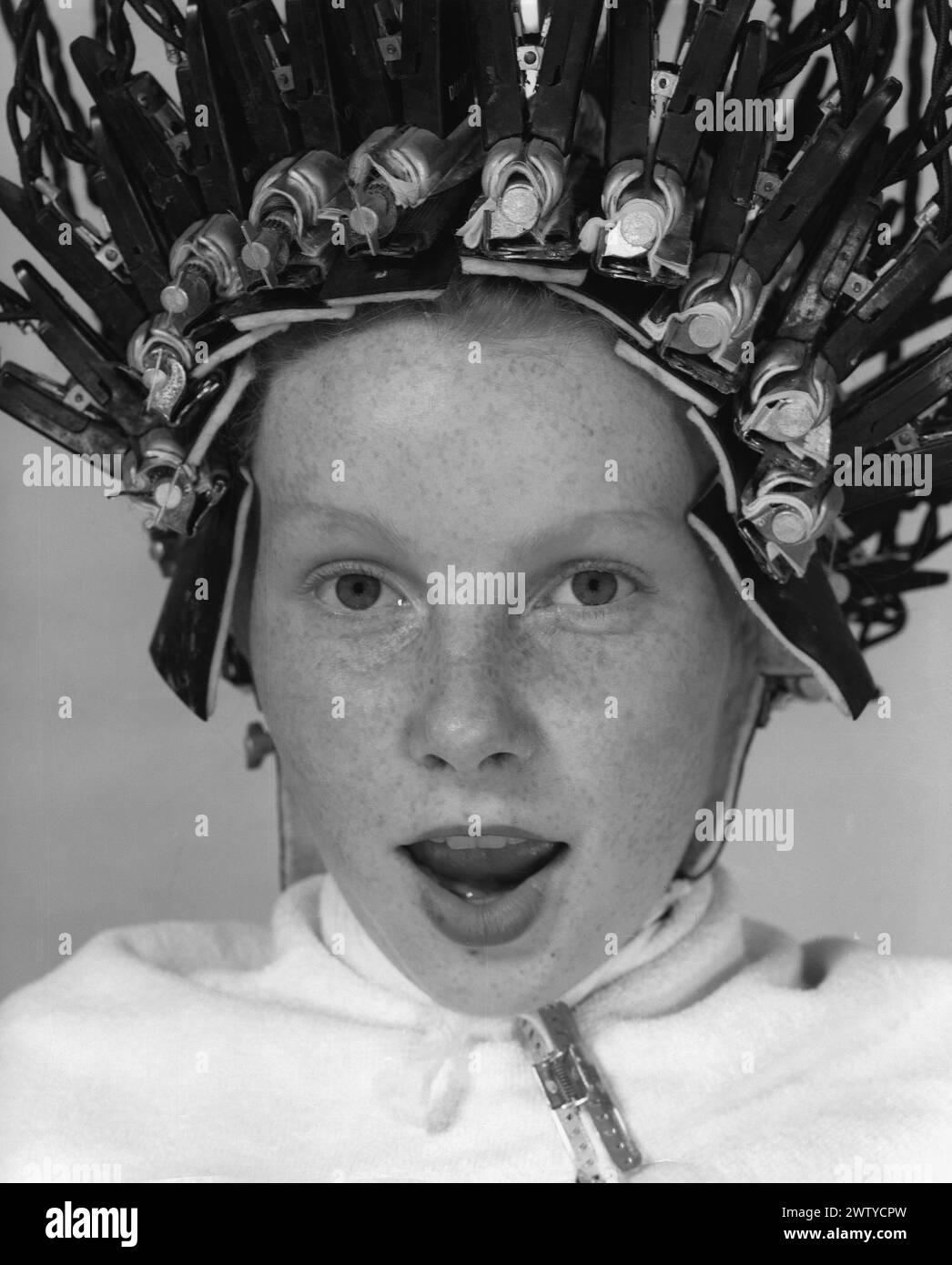 Freckle Faced Girl Looks Surprised As She Sits Having Her Hair Curled