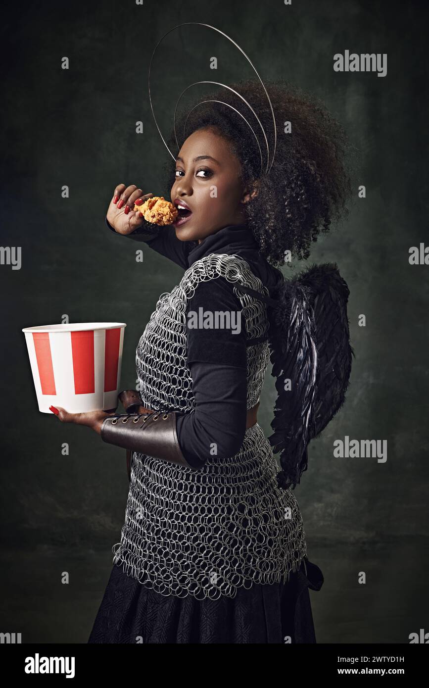 Young African woman, medieval warrior in chainmail armor eating chicken ...