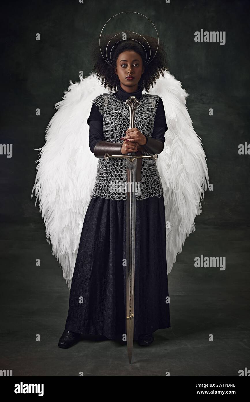 Young African woman with angel wings, halo above head and chainmail ...