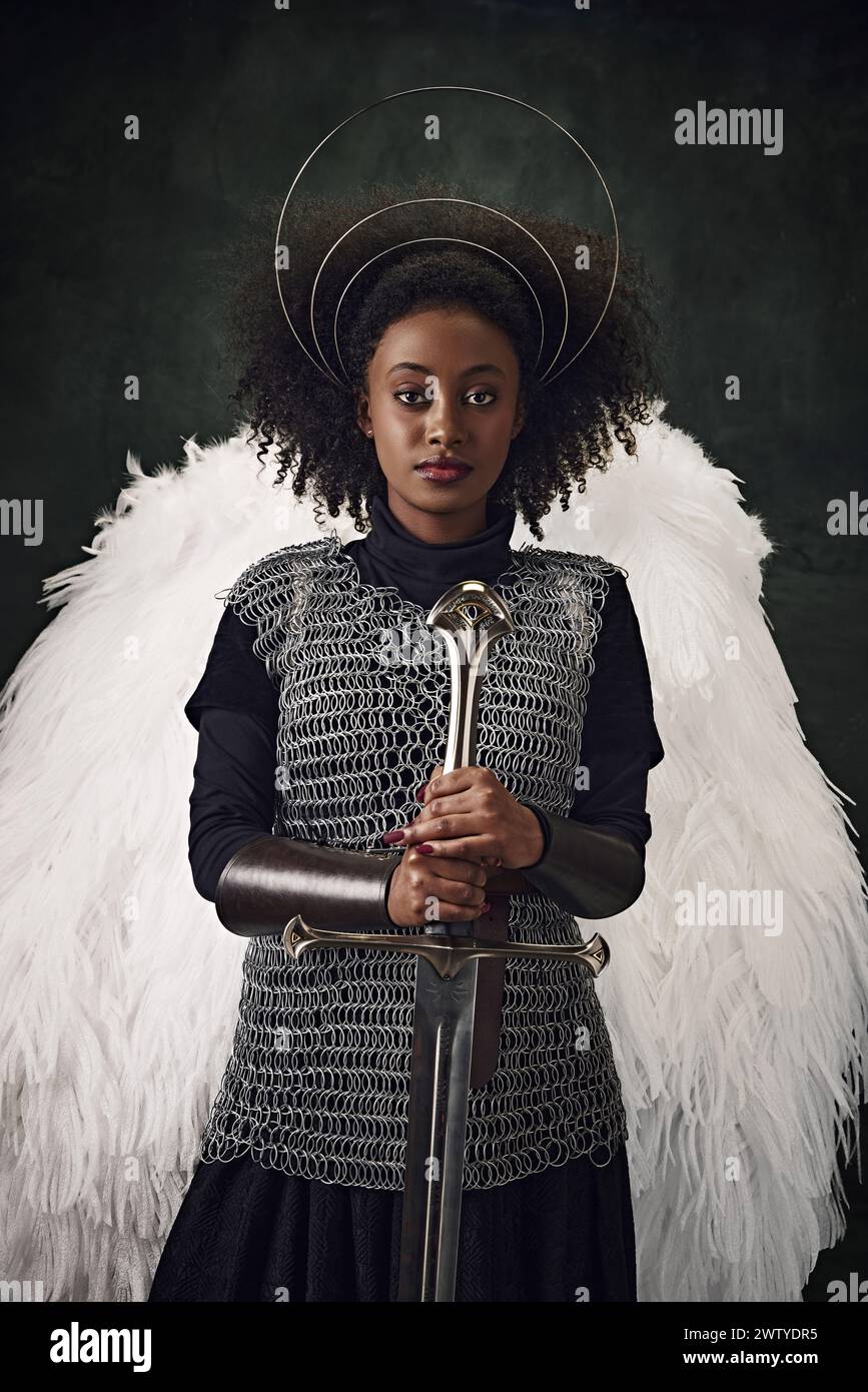 Young African woman with angel wings, halo above head and chainmail ...
