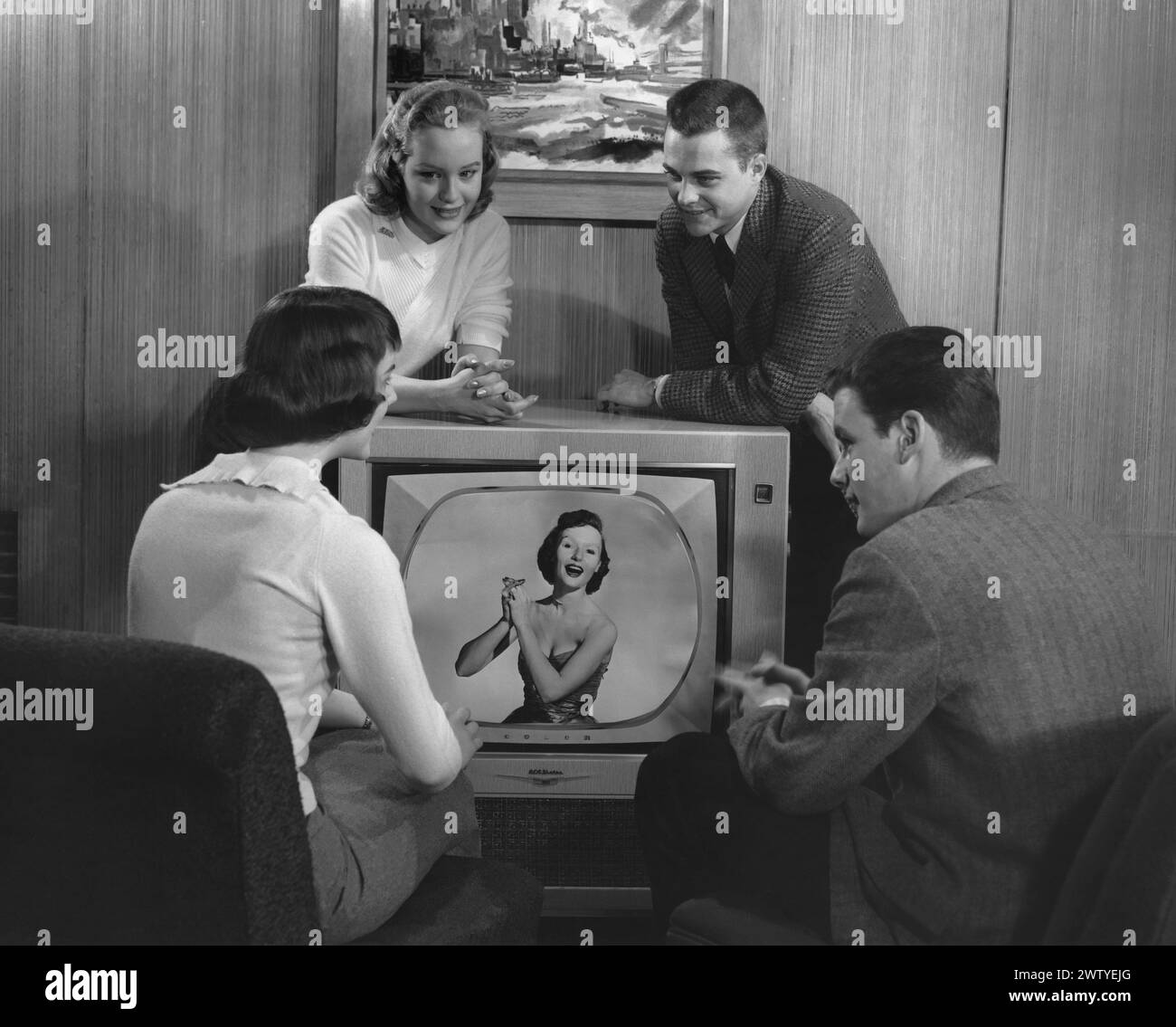 Two younger couples gathered around a television Stock Photo - Alamy