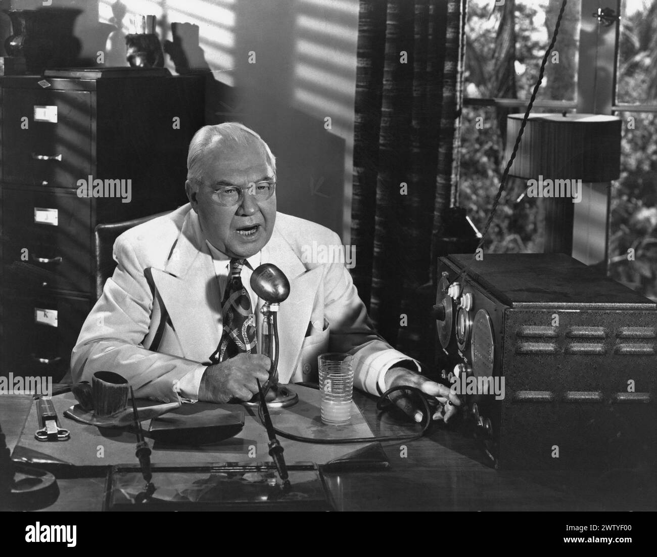 Actor George Barbier sitting in his home office broadcasting over radio ...