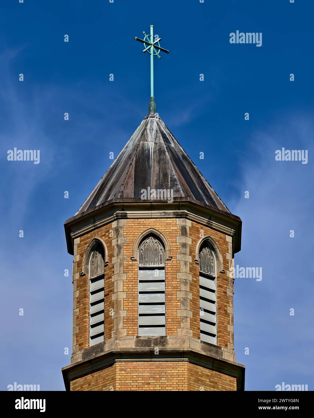 A closeup of a Church steeple with a cross and a beautiful blue sky and ...