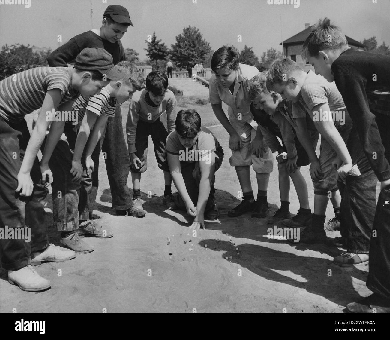 Group of nine young boys huddled in a circle, leaning down, watching ...