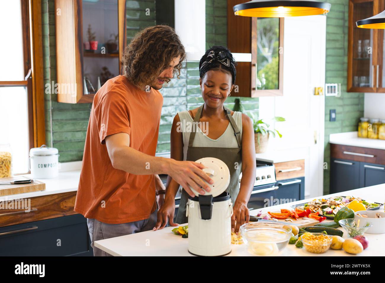 A diverse couple is putting food waste in compost bin together in the ...