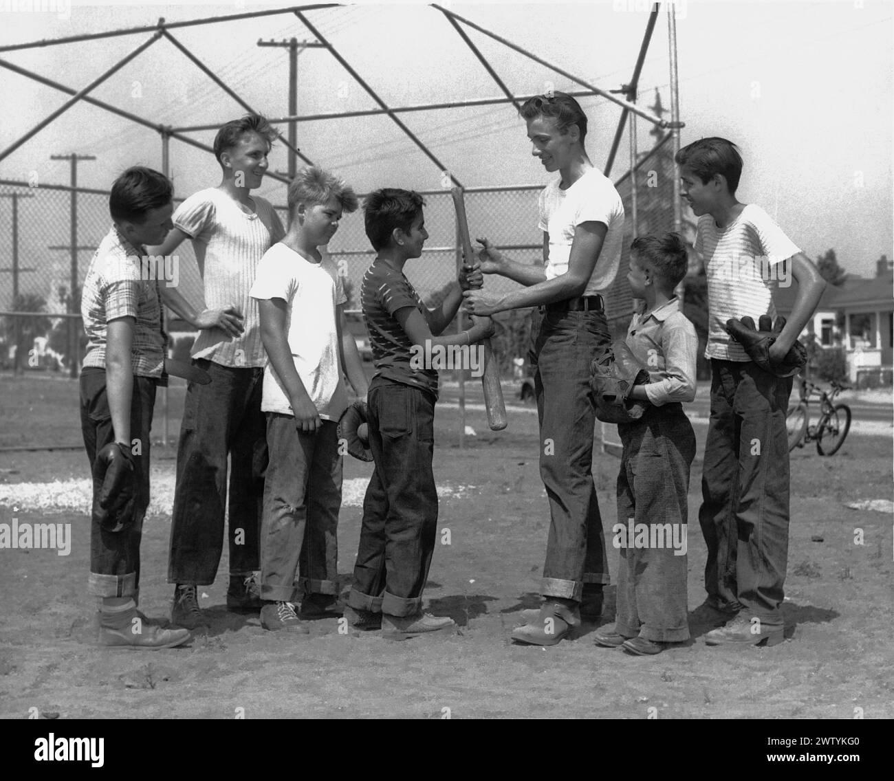 Teenage boys standing on a baseball field while two of them use a bat ...