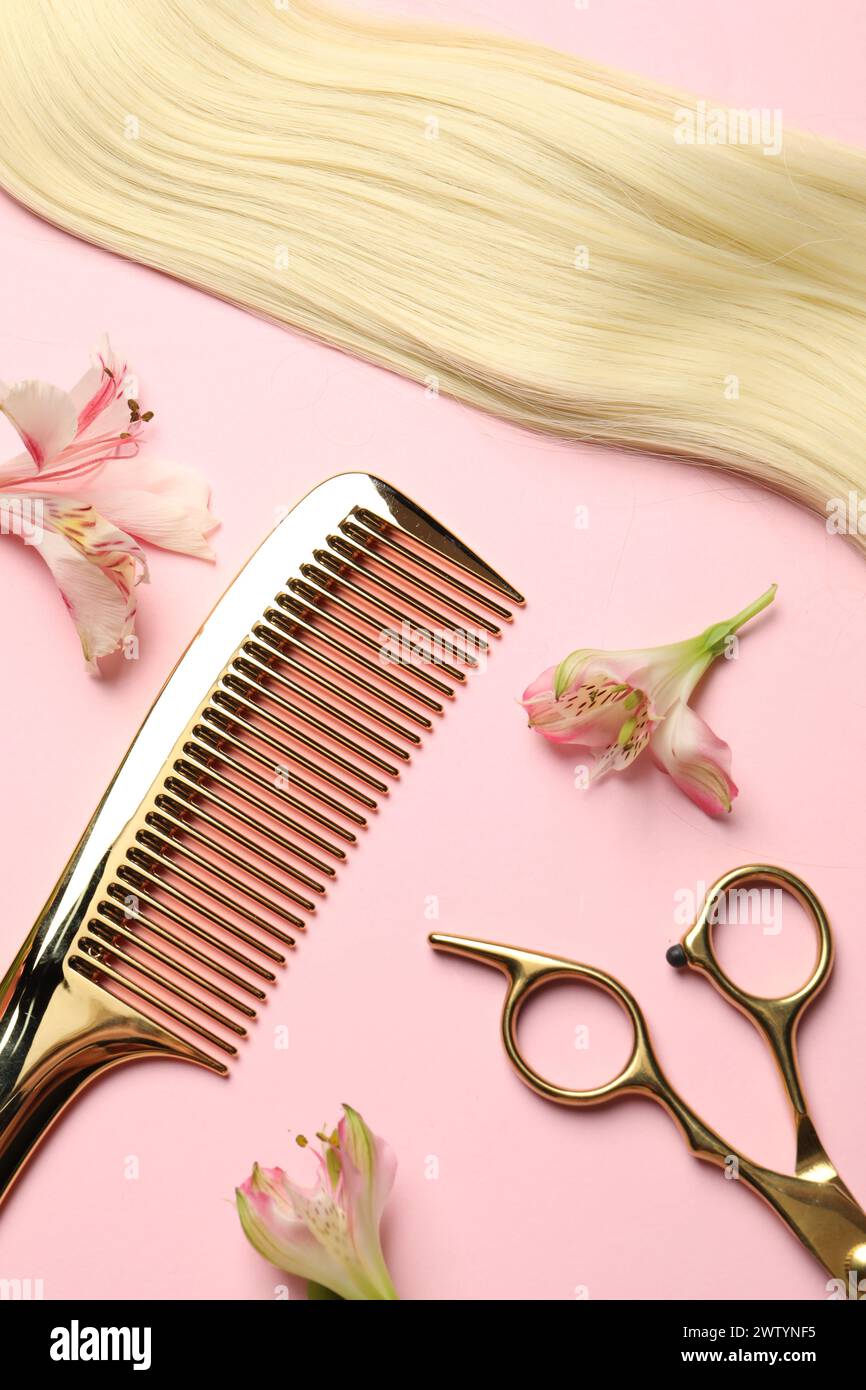 Hairdresser tools. Blonde hair lock, comb, scissors and flowers on pink ...