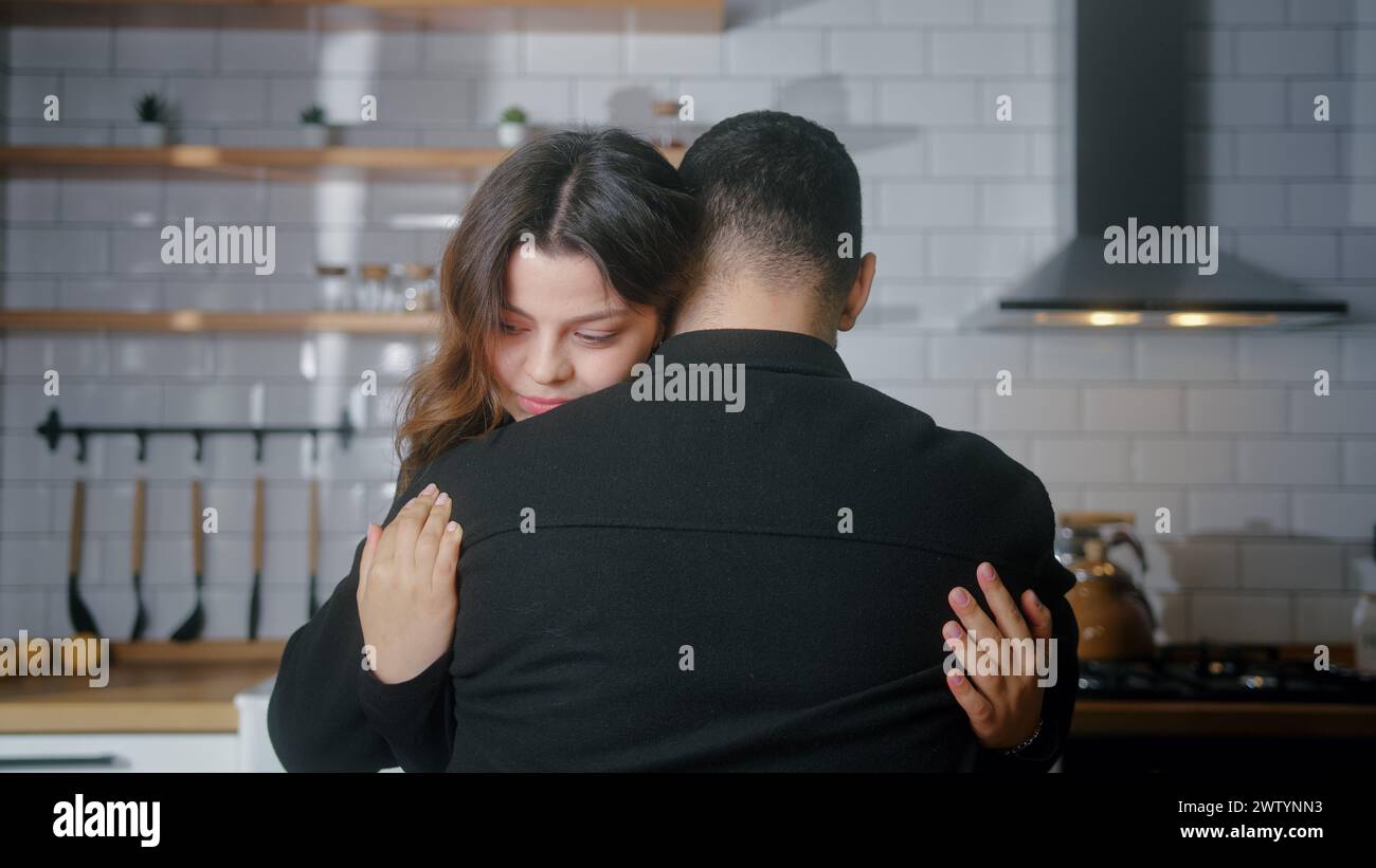 Rear view of man hugging her boyfriend. Beautiful woman hugging her lover in the kitchen. Medium ...