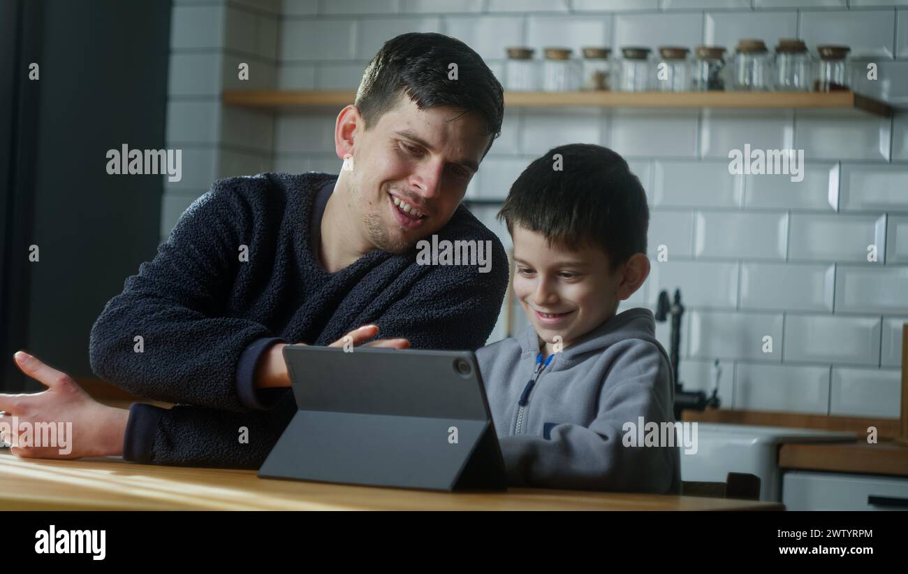 Young dad and son having fun using digital tablet sitting in the ...