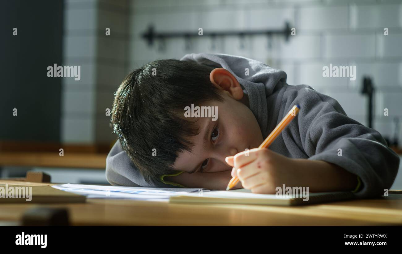 Tired little schoolboy kid lying on table desk writing homework, boring ...