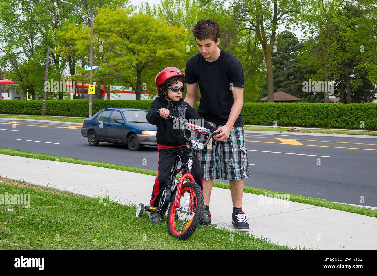 Male teen teaching his brother sibling child how to ride bicycle Stock ...