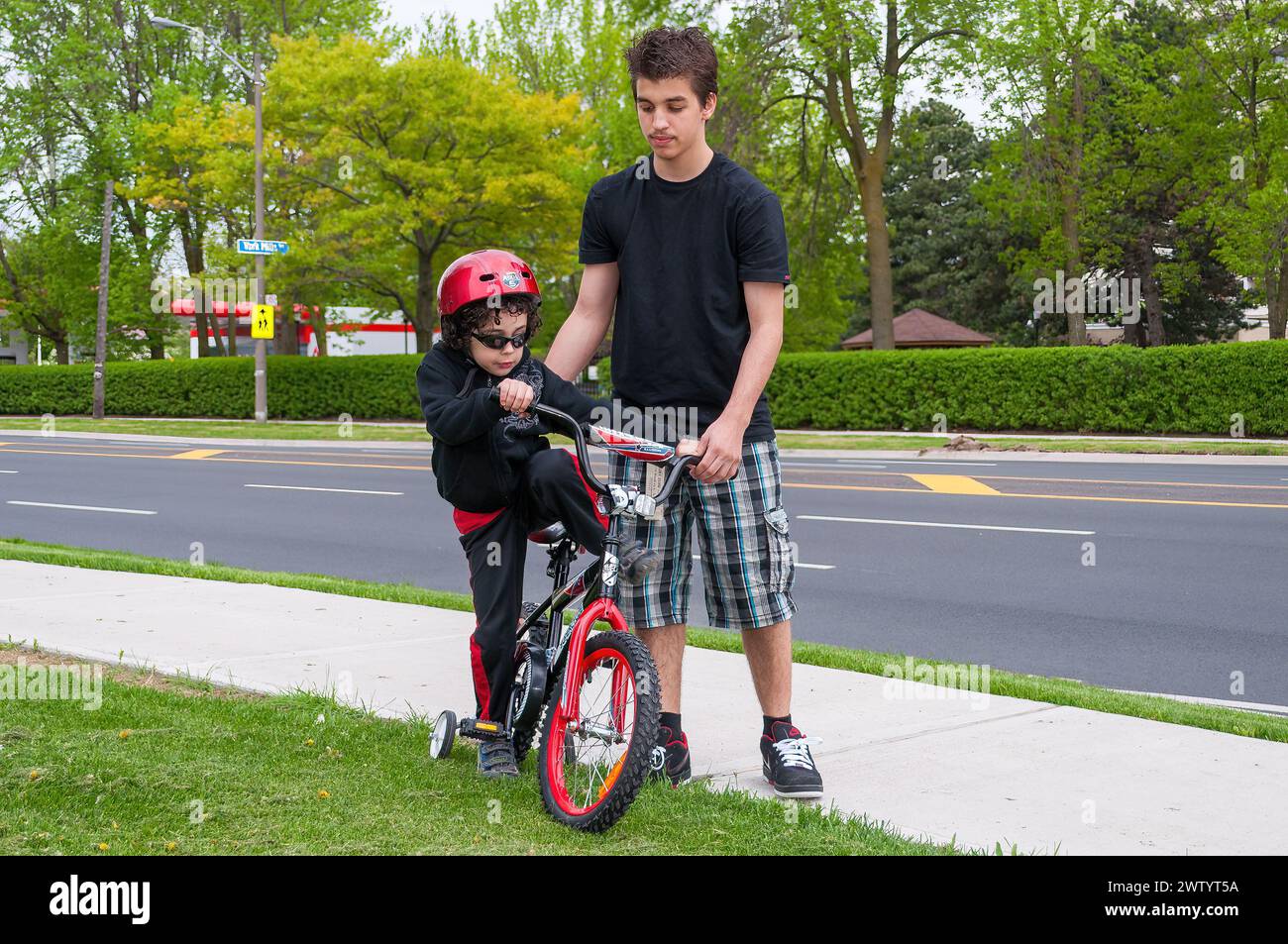 Male teen teaching his brother sibling child how to ride bicycle Stock ...