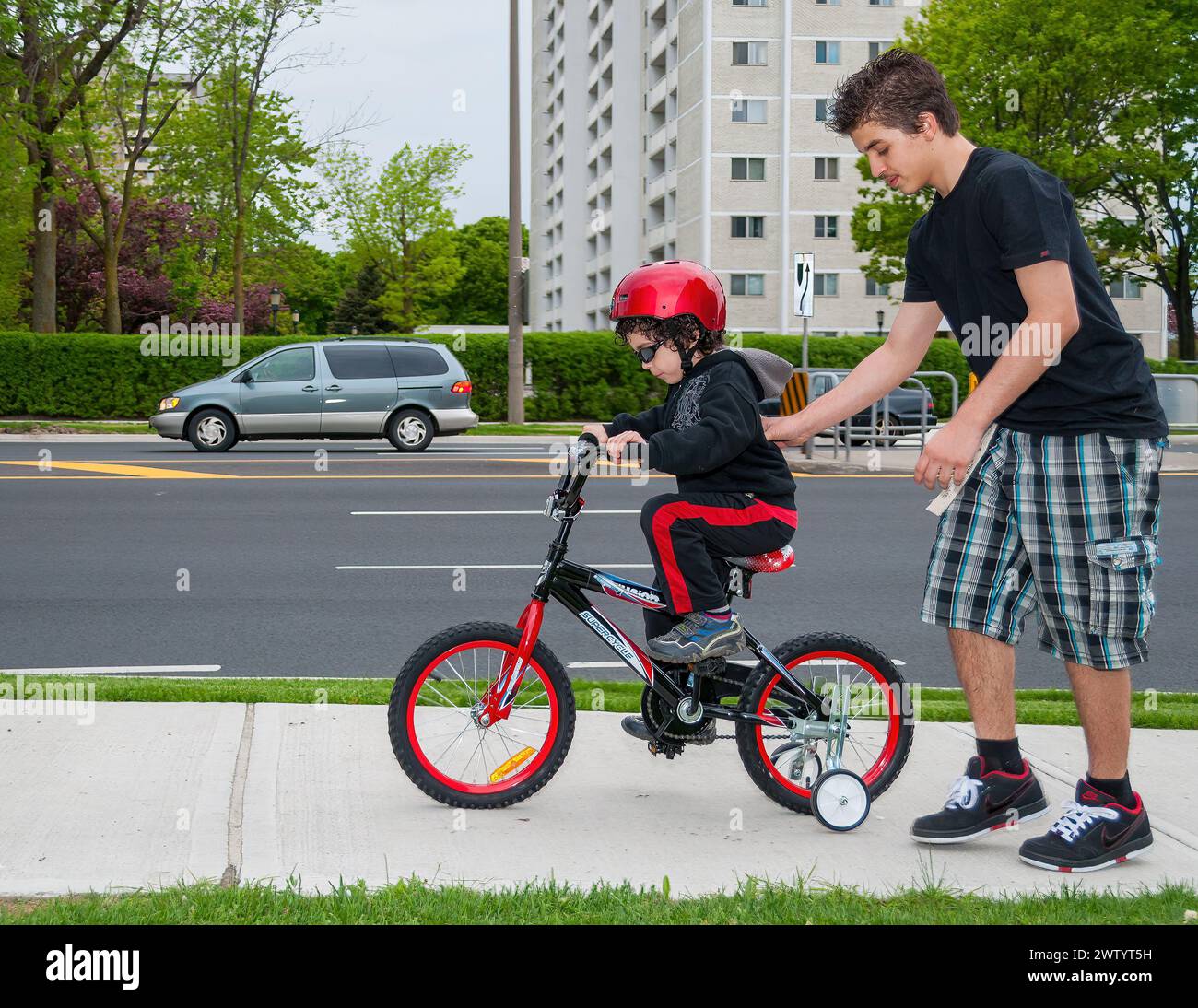 Male teen teaching his brother sibling child how to ride bicycle Stock ...