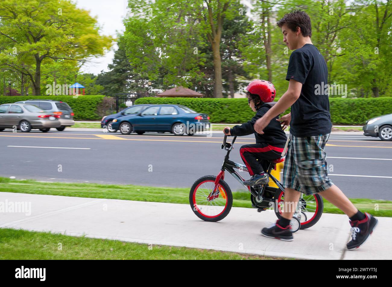 Male teen teaching his brother sibling child how to ride bicycle Stock ...