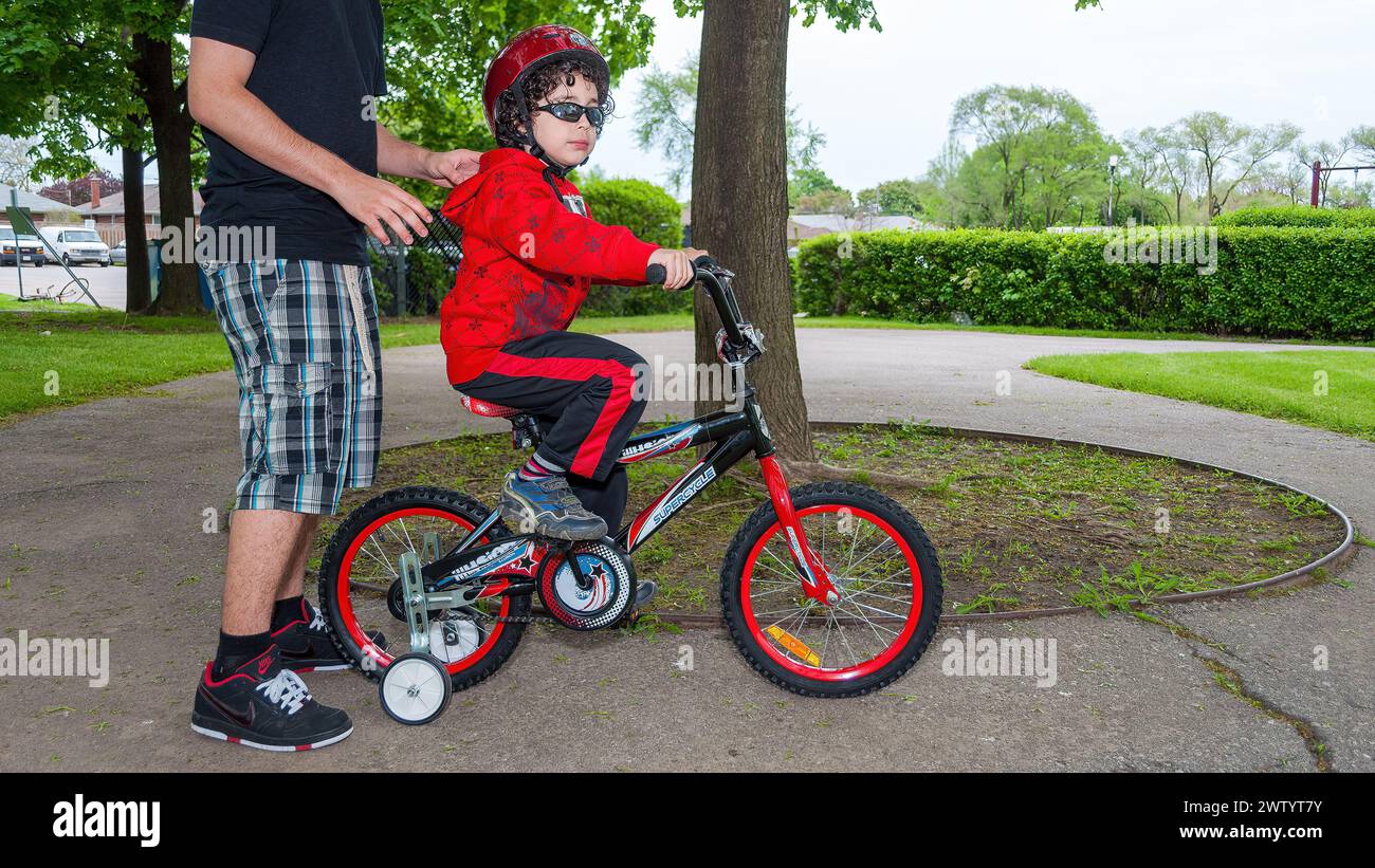 Male teen teaching his brother sibling child how to ride bicycle Stock ...
