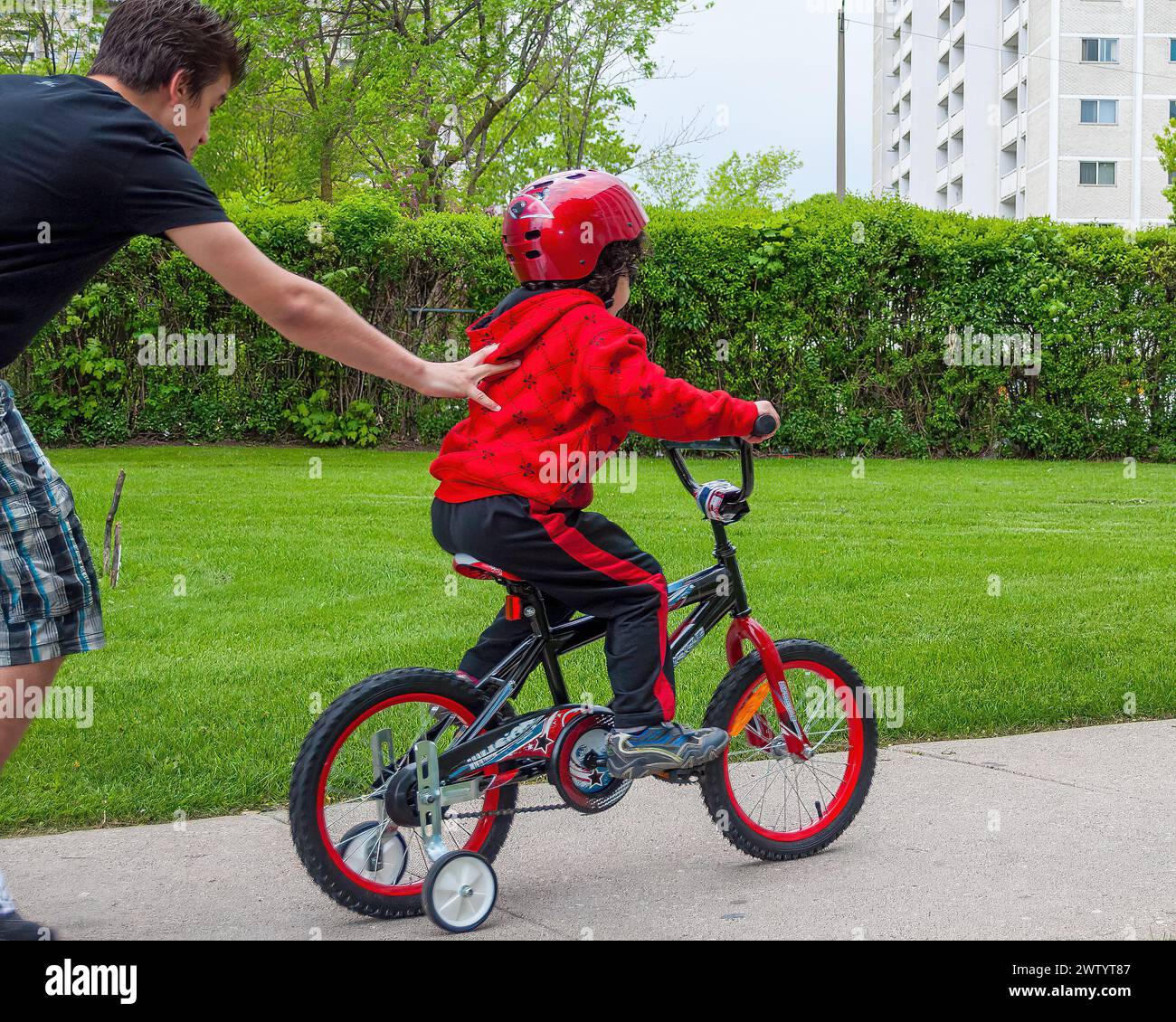 Male teen teaching his brother sibling child how to ride bicycle Stock ...