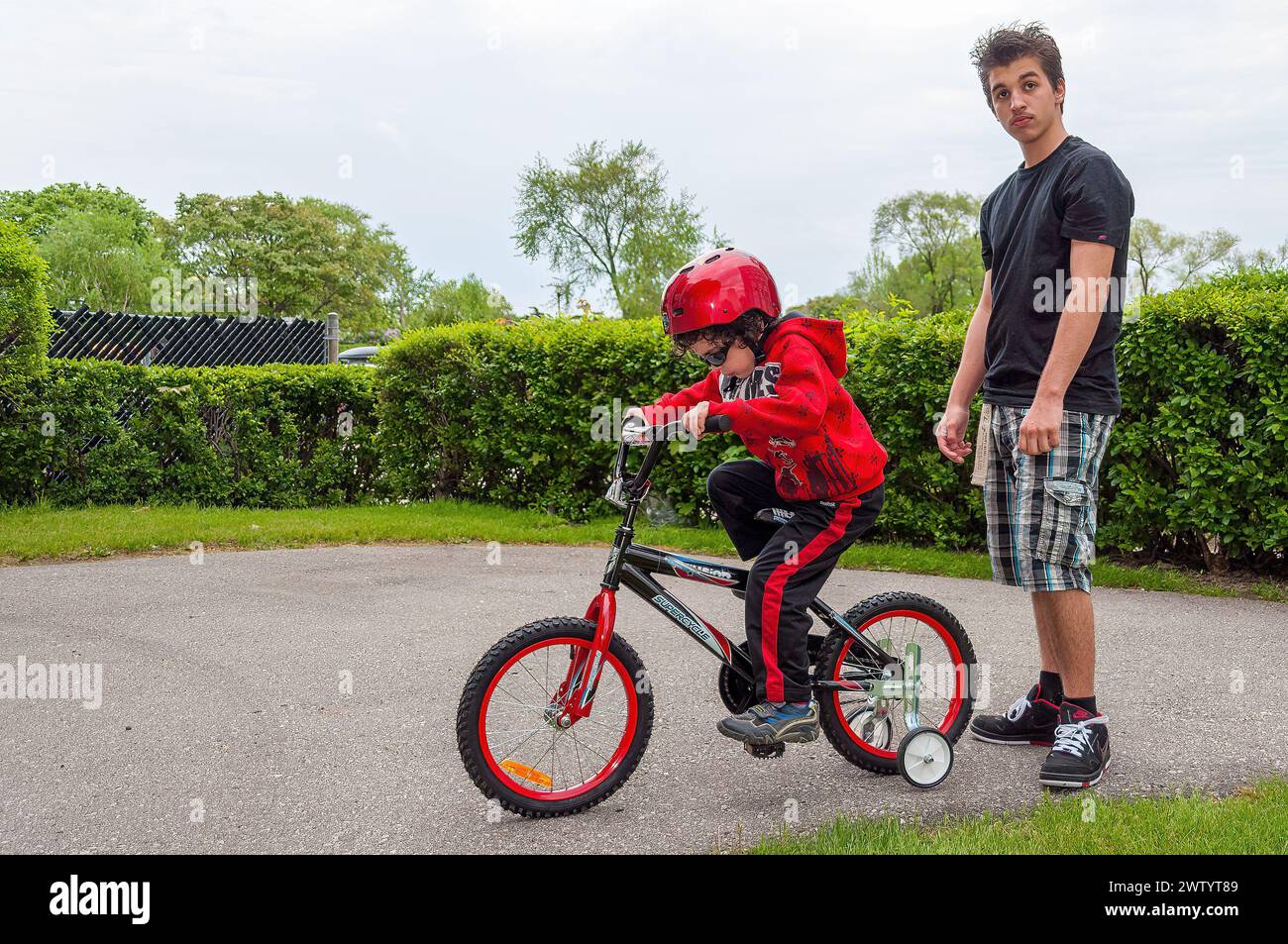 Male teen teaching his brother sibling child how to ride bicycle Stock ...