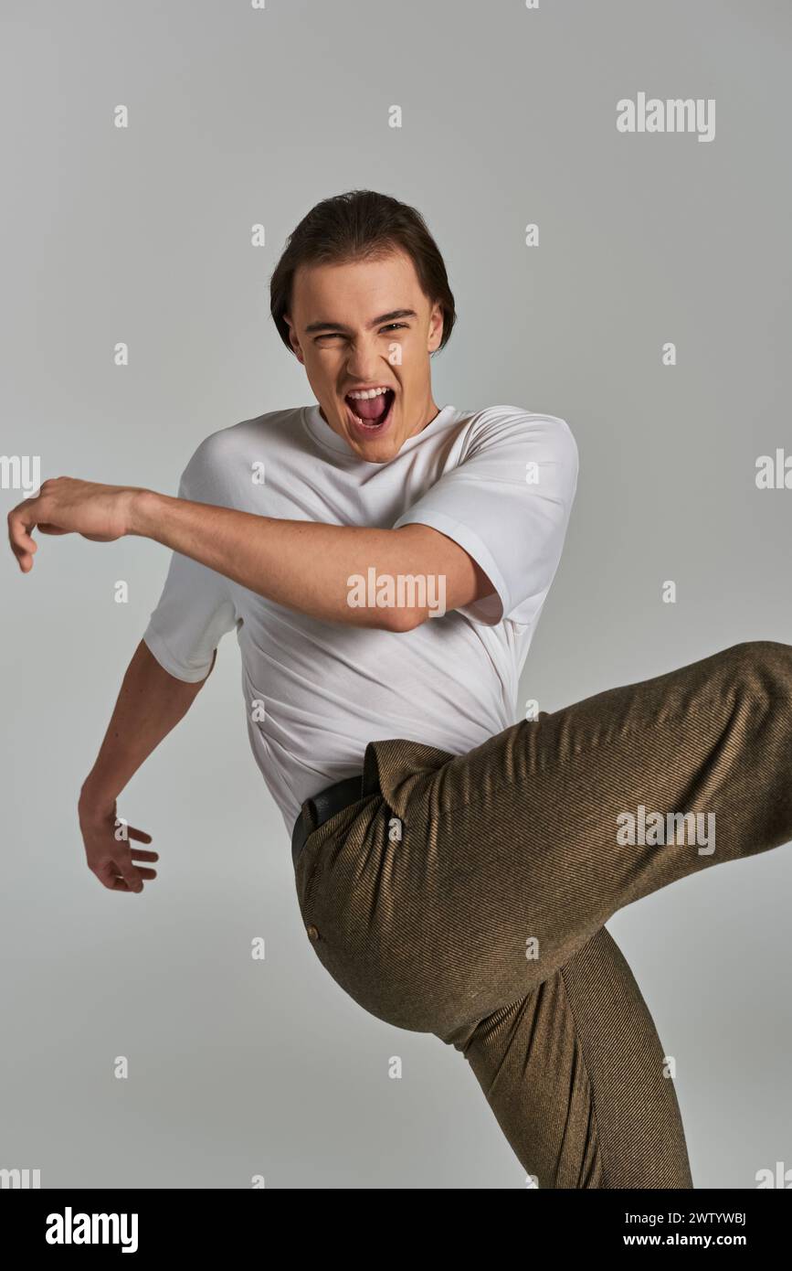 good looking joyous man in elegant attire posing in motion on gray ...