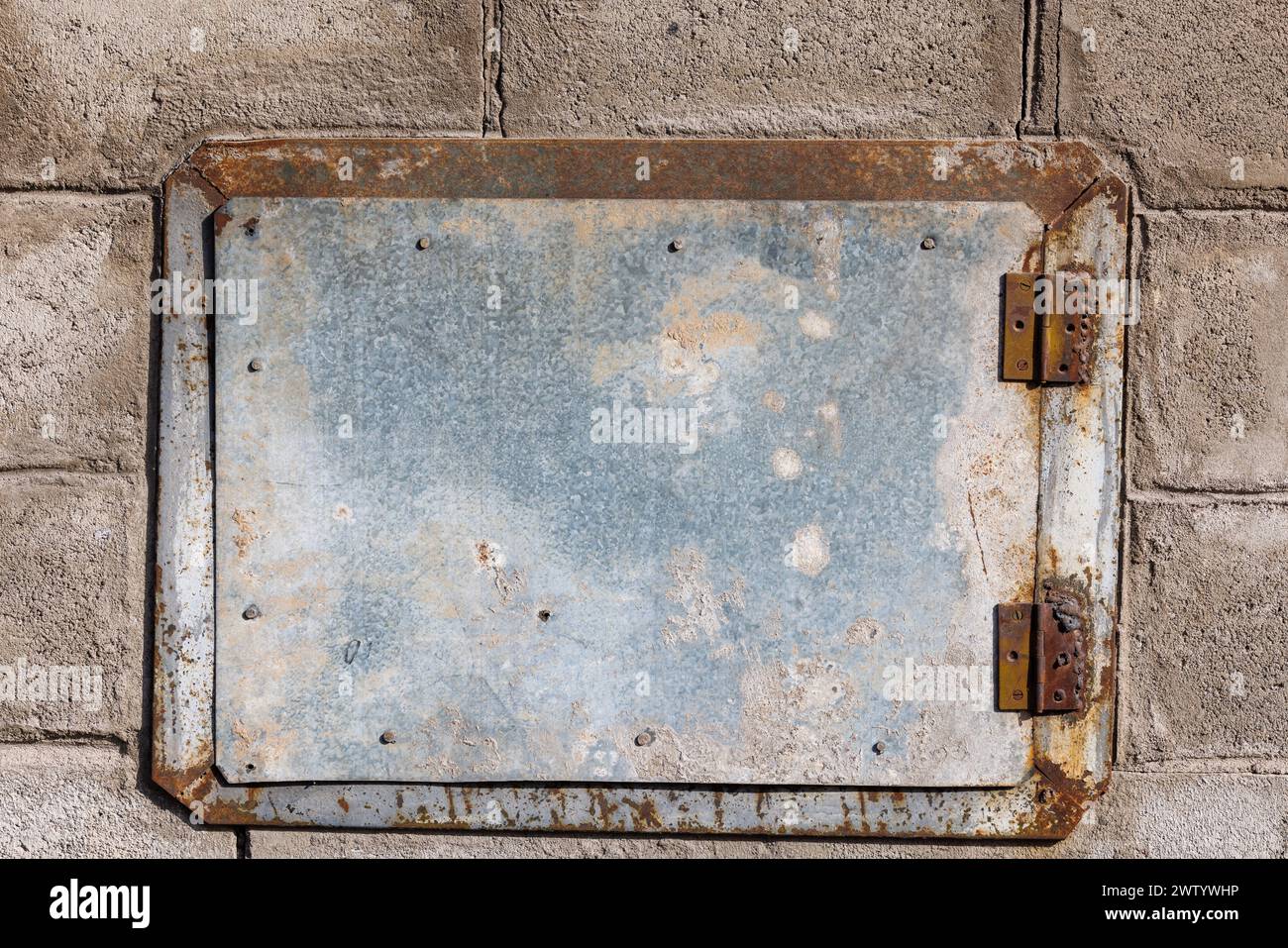 A small rectangular zinc coated metal hatch mounted on a brick wall ...