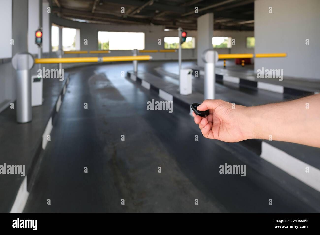 A hand using a remote control opens an automatic barrier in a parking ...