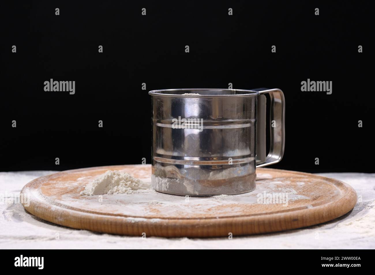 Iron sieve for sifting flour on the kitchen table, on a black ...