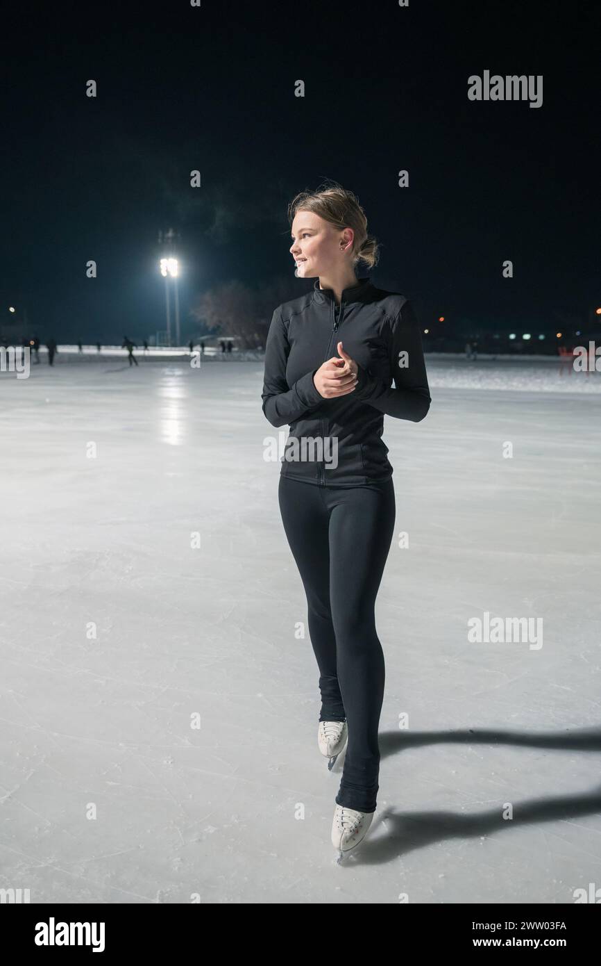 Beautiful young woman ice skating and performing she program over city ...