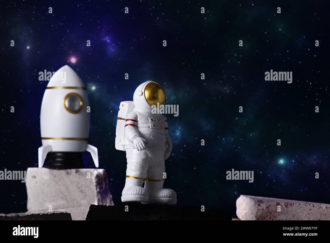 Figurine of astronaut and rocket over sky background, copy space. Toy ...