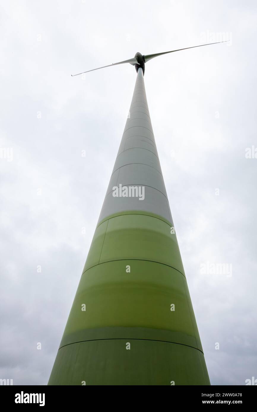 Green wind turbine tower is photographed from below at the wide angle. Sustainable energy ...