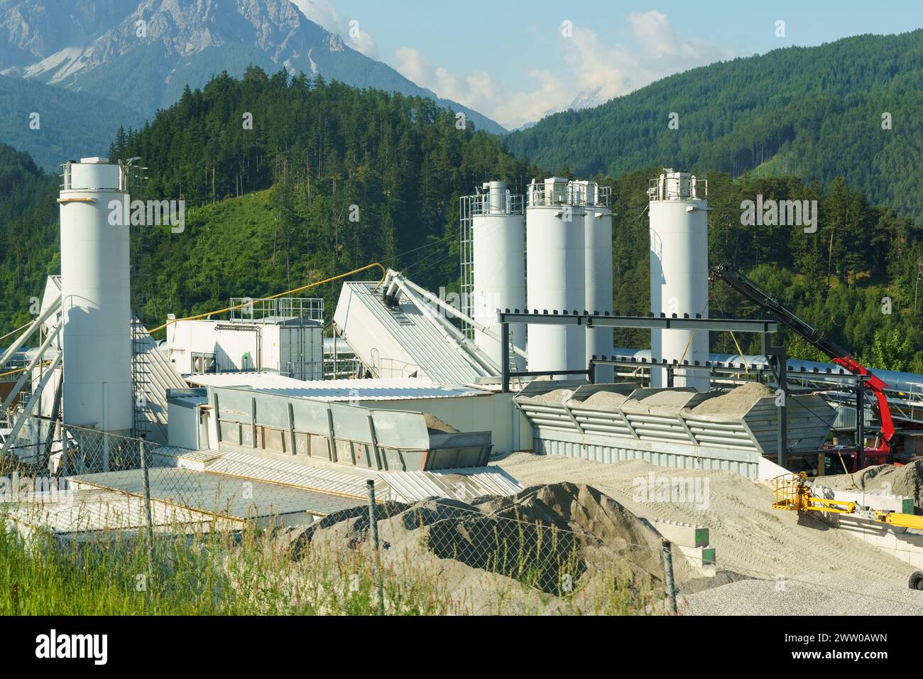 A busy cement factory with towering silos set against a backdrop of ...