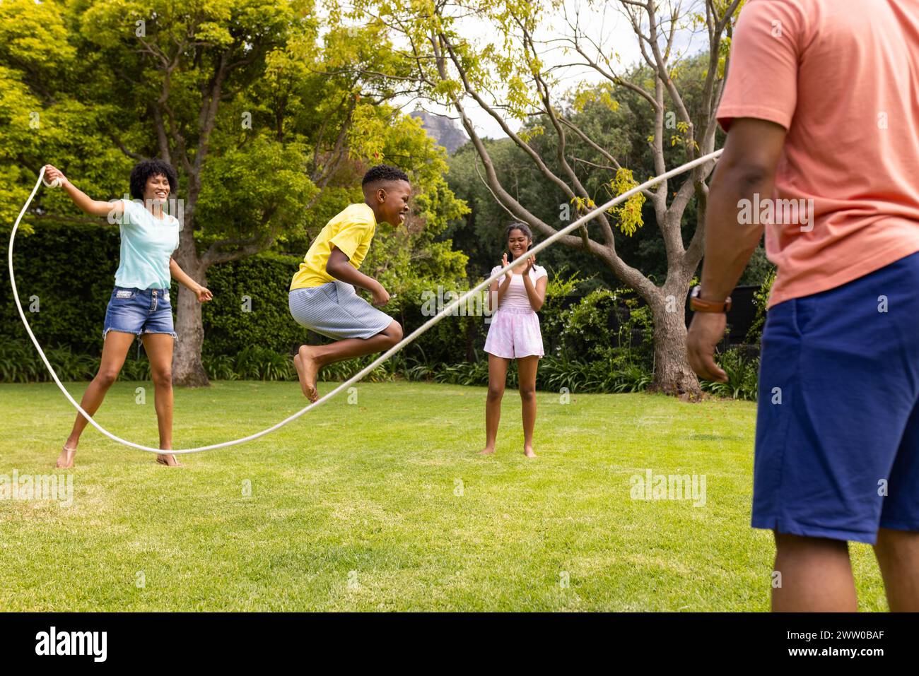 An African American family enjoys a sunny day playing with a jump rope ...