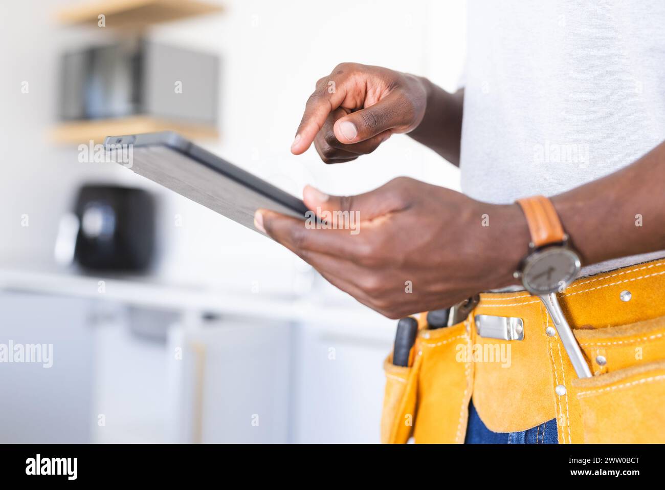 African American workman in tool belt interacts with a tablet Stock ...