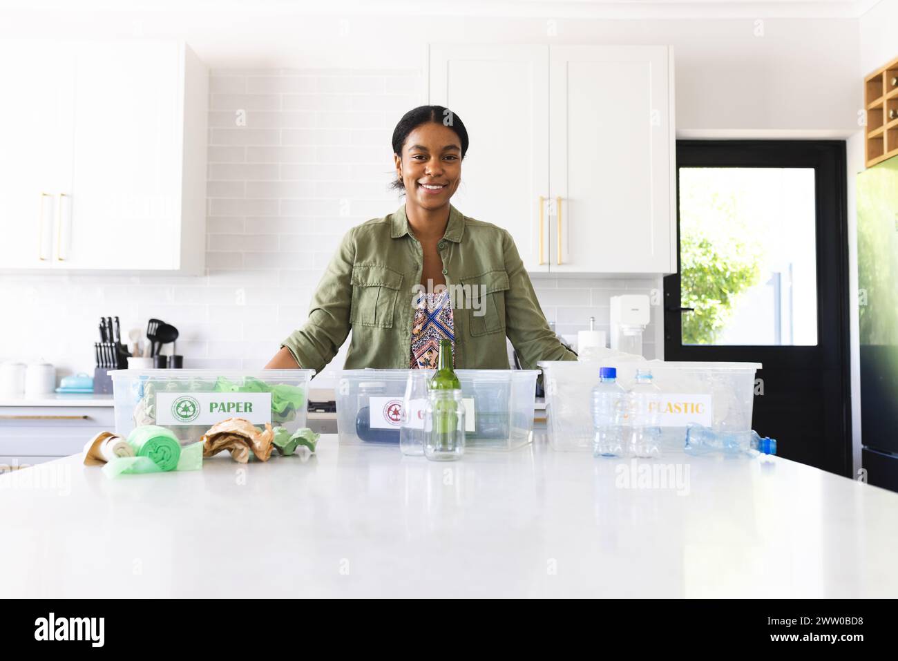 A young African American woman is sorting recyclables at home in the ...