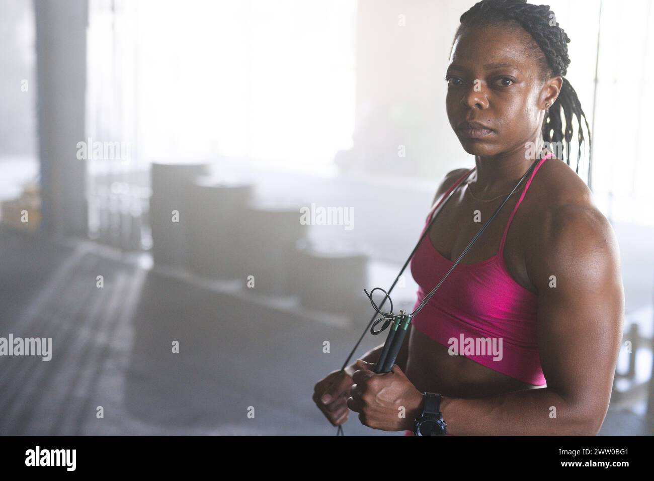 A fit African American strong woman stands confidently in the gym with ...