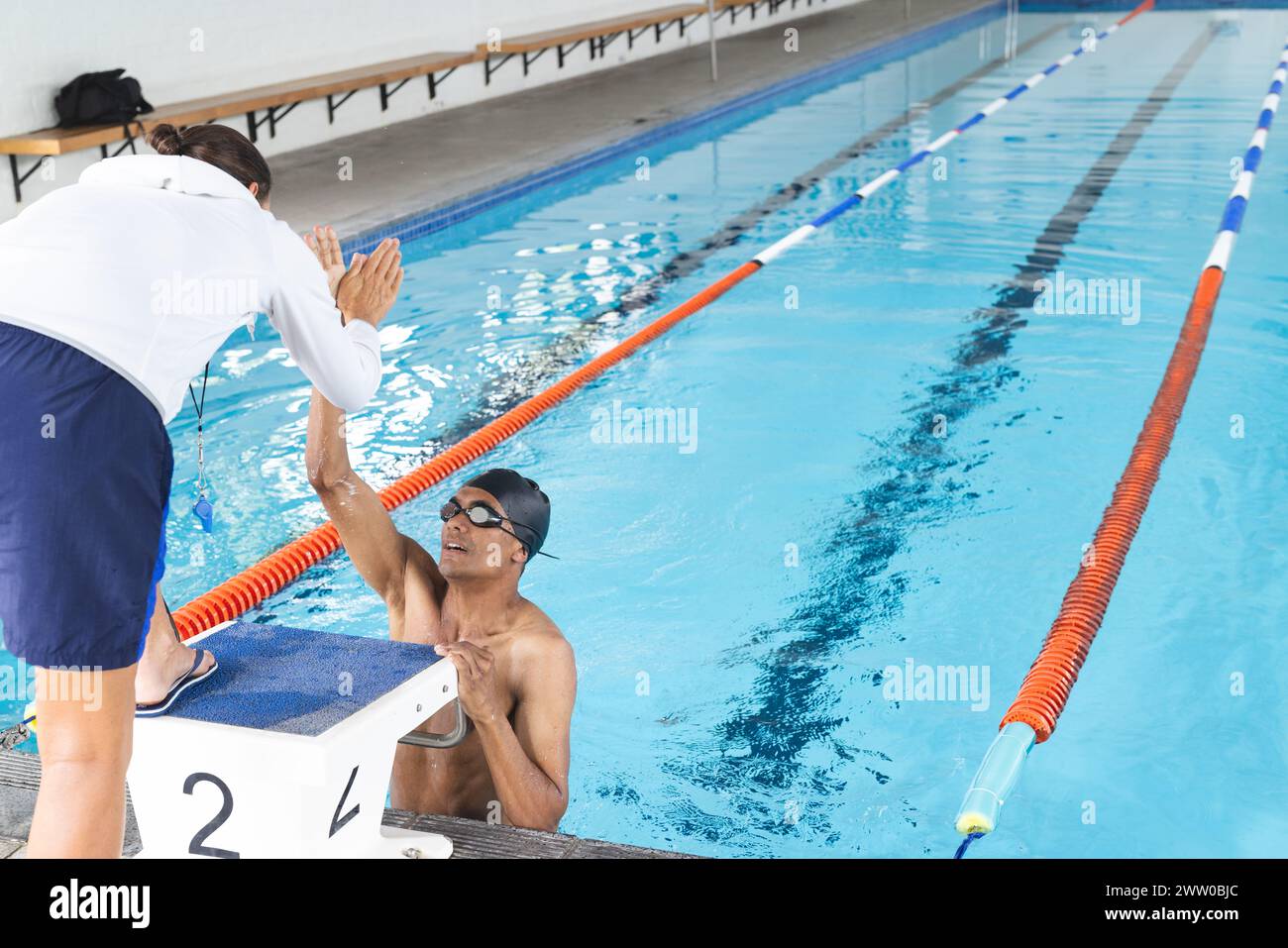 A fit African American male athlete swimmer is high-fiving his coach at ...