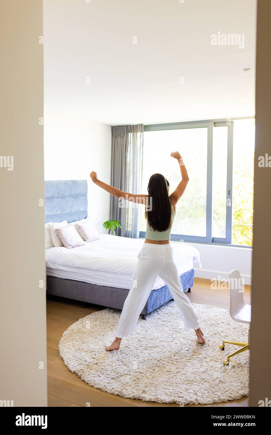 A young Caucasian brunette woman dances in her bedroom at home. She has ...