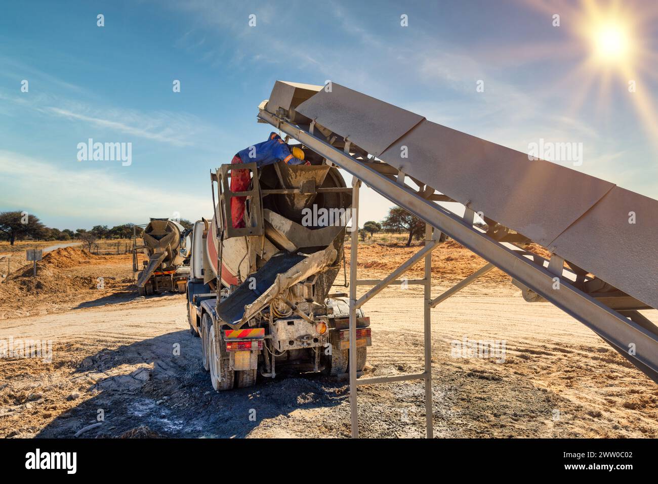 cement mixer truck, loaded by a conveyor belt, african worker on ...